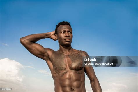 머리와 어깨를 닫습니다 젊은 매력적이 고 적합 흑인 아프리카계 미국인 남자 강한 근육 질의 몸 포즈 시원한 모델 태도 해변에 고립 된 여름 푸른 하늘 30 39세에 대한