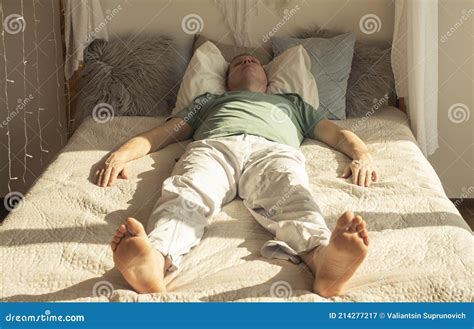 Ленивый человек спать или мечтая в дневное время с дневным светом на кровать в спальне Стоковое