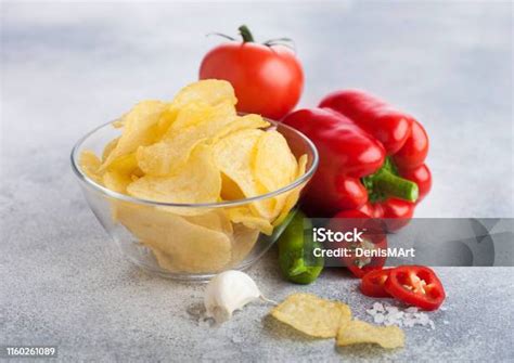 가벼운 테이블 배경에 양파 맛과 감자 파삭 파삭 칩 유리 그릇 접시 파프리카와 토마토를 곁들인 붉은 고추와 녹색 고추 0명에