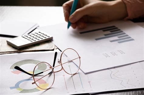 재무 보고서와 막대 그래프는 계산기와 안경 비즈니스 금융 옆의 책상에 놓여 있습니다 개념에 대한 스톡 사진 및 기타 이미지