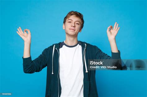 요가 제스처에 손을 잡고 캐주얼 옷에 젊은 남자의 초상화 스튜디오에서 파란색 벽 배경에 고립 명상 휴식 사람들은 진심으로 감정