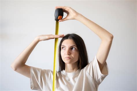 Premium Photo Young Girl Checking Her Height With A Yellow Measuring Tape Indoors