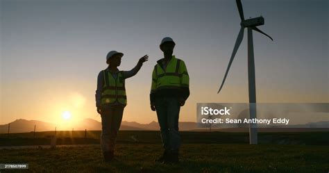 계획 엔지니어 및 팀은 발전소 유지 보수 검사 및 토론을 위해 일몰에 풍력 발전 단지에서 근무합니다 남자 여자 및 풍차는 발전기 건설 및 청정 에너지 야외 25 29세에