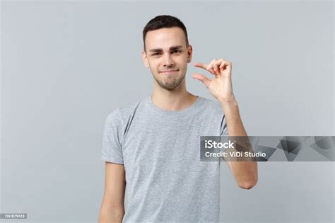 스튜디오에서 회색 배경에 고립 된 작업 영역으로 크기를 보여주는 캐주얼에서 젊은 남자를 의아해 사람들은 진심으로 감정 라이프 스타일 개념입니다 복사 공간을 모의 합니다 광고