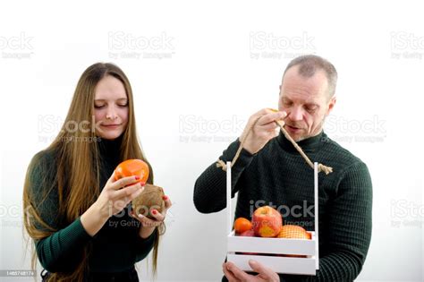 손에 과일 상자의 형태로 바구니를 들고 남자 젊은 여자는 그리드 사과와 감귤 맛있는 건강 식품 열대 국가 건강 식품 과일 가게에서 감과 코코넛 자몽을 꺼냈다 감에 대한 스톡