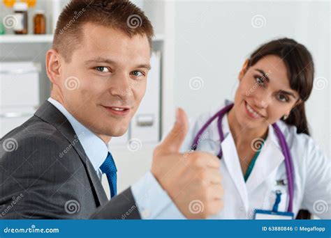 Усмехаясь человек в костюме показывая ОДОБРЕННЫЙ знак с большим пальцем