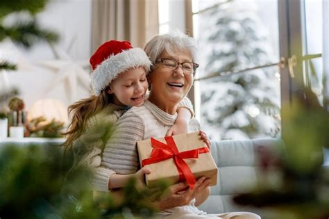 Merry Christmas And Happy Holidays Cheerful Grandma And Her Cute Grand Daughter Girl Exchanging