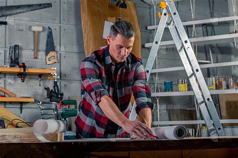 一个木匠的工作原理。木匠研究绘图项目。以研讨会为背景