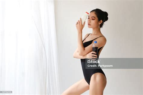 다이어트 또는 좋은 건강 개념 건강하고 스포티 한 아시아 젊은 여성이 검은 운동복을 입고있다 우유와 청량 음료 한 병을 들고있는 매력적인 소녀 그녀는 건강하거나 건강에
