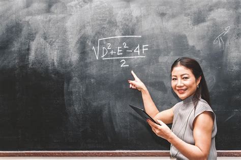 Premium Photo Portrait Of Teacher Pointing At Formula On Blackboard In Classroom