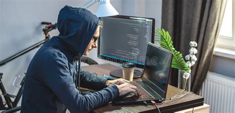 Hacker In The Hood Is Programming Virus Code At The Keyboard For The Laptop Internet Fraud And