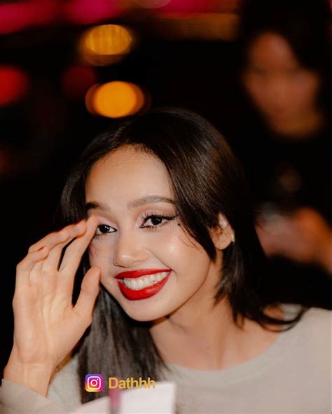 The Woman Is Smiling And Holding Her Hand Up To Her Face