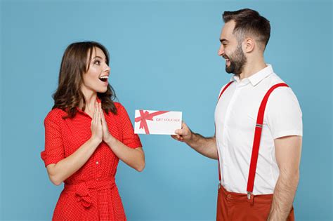 ตื่นเต้นร่าเริงมีความสุขคู่หนุ่มสาวสองเพื่อนชายหญิงสวมเสื้อผ้าสีแดงสีขาวถือบัตรของขวั ภาพสต็อก