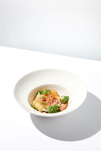 거친 그림자가있는 흰색 테이블에 게 고기 에스푸마 소스 및 양상추를 곁들인 우아한 샐러드 여름 메뉴에 게와 크림 소스를 곁들인 그린 샐러드 미적 음식 해산물 전채 갈고리