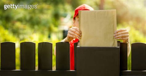 Postman Mail Carrier Inserting Blank Postal Envelope Into Mailbox Over