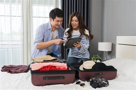 태블릿을 쓰고 집에서 침대에서 여행 가방에 옷을 포장하는 부부는 여행 휴가를 계획합니다 35 39세에 대한 스톡 사진 및 기타 이미지 35 39세 가정 생활 계획