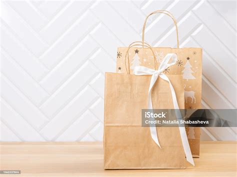 흰색 벽 배경이 있는 나무 베니어 테이블의 오른쪽 을 향하고 왼쪽으로 복사 공간을 제공하는 빈 종이 캐리어 가방 가방에 대한 스톡 사진 및 기타 이미지 Istock