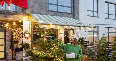 그녀의 Counry 집의 아름다운 뒤뜰에서 크리스마스 트리를 장식하는 여자 겨울 방학 준비의 개념 녹색 스웨터와 모자를 쓴 백인 여성 광각보기 사진 Unsplash