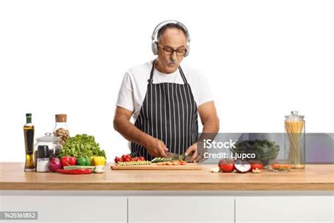 부엌 카운터에서 야채를 자르고 헤드폰으로 음악을 듣는 성숙한 남자 노인 남자에 대한 스톡 사진 및 기타 이미지 노인 남자 앞치마 요리하기 음식 준비 Istock