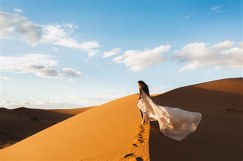 일몰 빛에 사하라 사막 모래 언덕의 환상적인 전망과 놀라운 실크 웨딩 드레스를 입은 여자 모로코 아프리카의 풍경입니다 갈색 머리에 대한 스톡 사진 및 기타 이미지 Istock