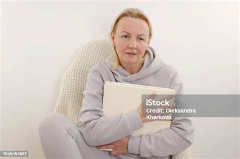 밝은 색의 운동복에서 무언가를 기억하는 꿈을 꾸는 앨범을 껴안는 여자 흰색 베이지색 페이지가 있는 앨범을 손에 들고 광고를 위한 빈 공간을 엽니다 꿈을 기다리는 머리카락을