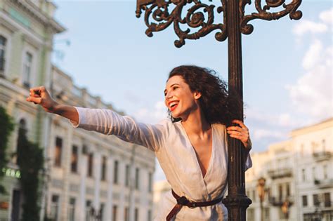 하얀 재킷을 입은 젊은 미소 짓는 아가씨가 행복하게 거리에서 시간을 보내는 동안 옆으로 쳐다보는 모습 20 24세에 대한 스톡 사진 및 기타 이미지 Istock