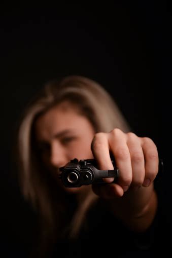 어린 소녀는 권총에서 프레임을 조준하며 양손으로 들고 있습니다 권총만 집중하고 흐릿한 배경에 있는 소녀 여성에 대한 스톡 사진 및 기타 이미지 Istock