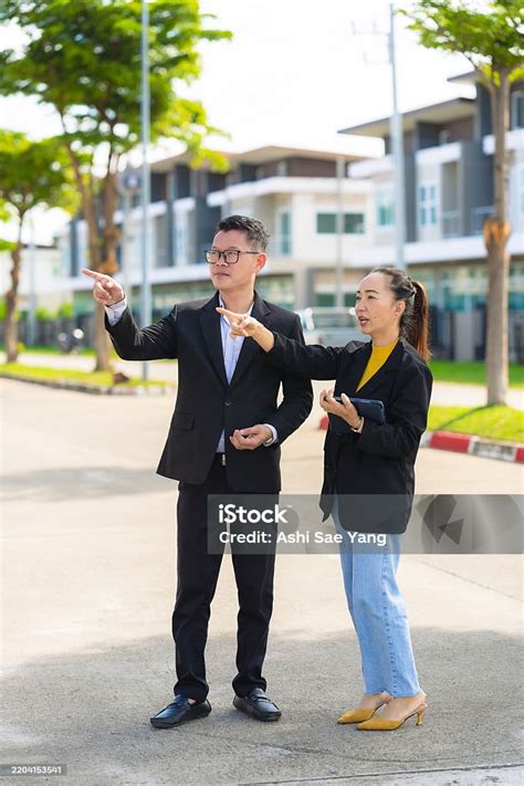 양복을 입은 꽃미남 부동산 사업가가 공사 중 집 앞에 서서 태블릿을 사용하여 건축주와 약속을 잡는 모습 세로 이미지 2명에 대한 스톡 사진 및 기타 이미지 Istock