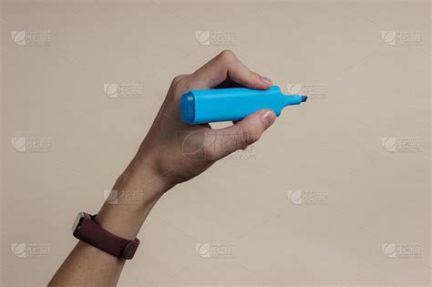 女性的手拿着一支蓝色毡尖笔在黄色蜡笔背景。俯视图