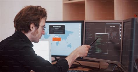 젊고 위험한 해커는 민감한 데이터를 다운로드하고 바이러스를 활성화하여 정부 서비스를 분해합니다 한 남자가 모니터가 많은 랩톱 컴퓨터를 사용합니다 사진 Unsplash