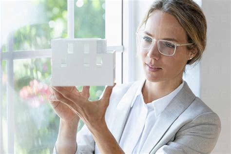 Female Professional Checking Architectural Model By Window In Office