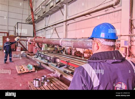 Men Using A Lift And A Crane To Move Big Heavy Metal Objects Like Pips