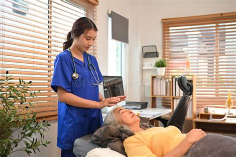 Physiotherapist Doing Reiki Treatment Session To Mature Woman At Clinic