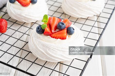 파플로바 머랭 케이크와 휘핑 크림 신선한 베리가 화이트 우드 배경의 쿨링 랙 위에 있습니다 여름 디저트 공간을 복사합니다 블루베리에 대한 스톡 사진 및 기타 이미지 Istock