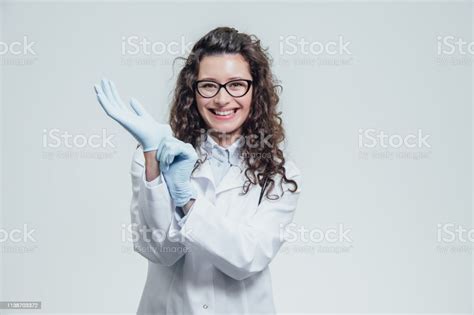파란 장갑에 안경을 착용 하는 젊은 여자 닥터는 카메라에 열심히 보인다 회색 배경에 고립 실험실에 대한 스톡 사진 및 기타 이미지 실험실 미소 한 명의 여자만