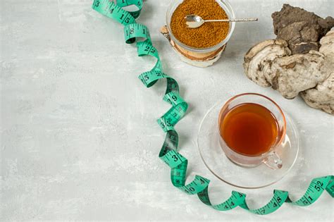 차가 자작나무 버섯은 다이어트와 면역을위한 트렌디 한 슈퍼 푸드입니다 유리 컵에 천연 차 커피와 자작 나무 차가 조각 가벼운 배경에 테이프를 측정 천연 항산화제 공간을