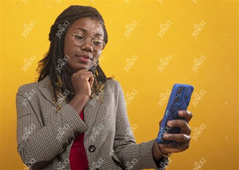 Jeune femme africaine regardant son téléphone sur un fond jaune Photo 6652 Jolixi Banque