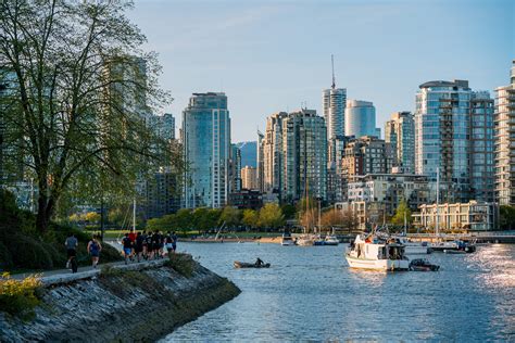 A Group Of People Walking Along A River Next To Tall Buildings Photo