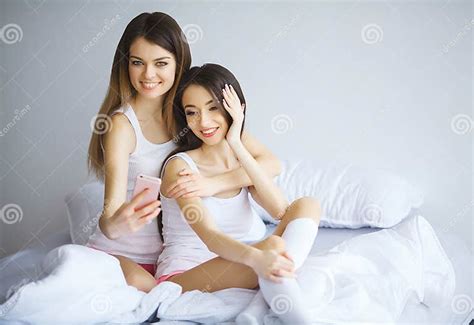 Two Hot Girls Lying On A Bed Taking A Photo Of Themselves Stock Image