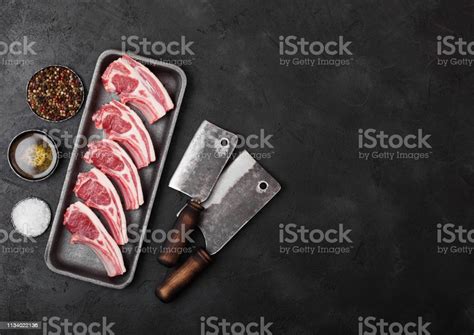 검은 바탕에 빈티지 고기 모자를 가진 플라스틱 쟁반에 신선한 생 정육점 양고기 쇠고기 절단 수 있습니다 강철 보 울에 있는 소금 후추 및 기름 텍스트 공간 고기에 대한 스톡