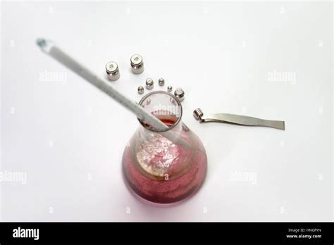 Chromed Laboratory Weights And Steel Tweezers Near The Flask Of Pink Liquid And Precipitated