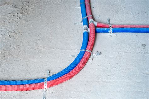 파란색과 빨간색 플라스틱 골판지 튜브가 바닥을 가로질러 뻗어 있습니다 건물의 수리 또는 건설 중에 열 및 물 공급의 임시 통신 파이프 연결 지점 0명에 대한 스톡 사진 및