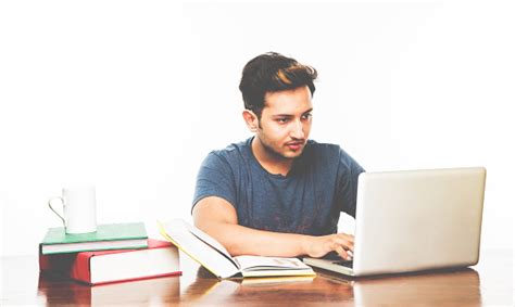 잘생긴 인도 소년 또는 남자 대학생 공부 하 고 연구도 서의 더미와 함께 테이블에 노트북 컴퓨터와 커피 낯 짝 미소 또는 생각 걱정 또는 엄지손가락 표시 또는