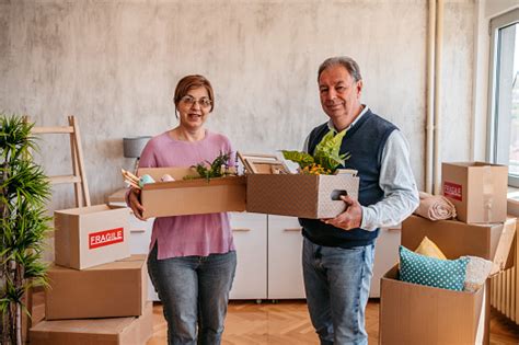 새로운 가정에서 식물과 사진 프레임 상자를 들고 있는 시니어 커플 2명에 대한 스톡 사진 및 기타 이미지 2명 60 69세 가구 Istock