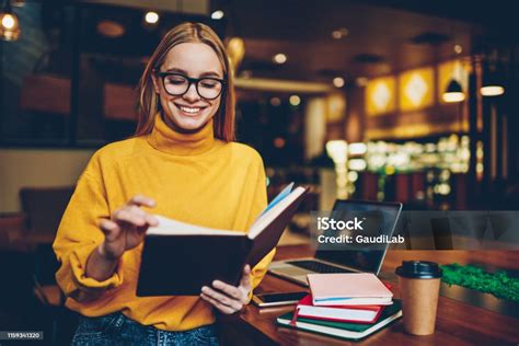 커피숍에서 시간을 보내는 동안 진심으로 웃고 캐주얼 옷을 입고 매력적인 감정 재능있는 여학생 아름다운 성공적인 힙스터 소녀 읽기