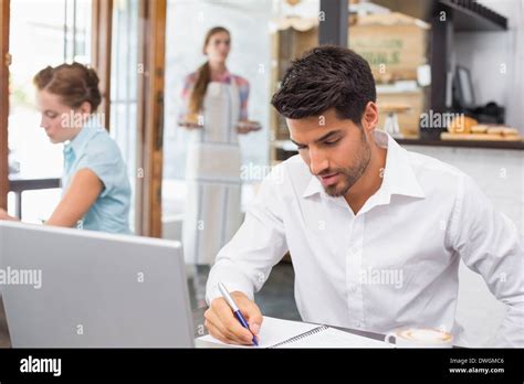 Man Writing Notes With Laptop In Coffee Shop Stock Photo Alamy