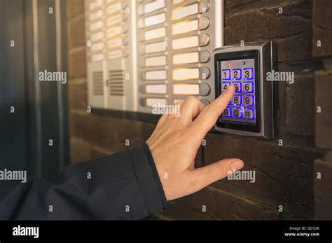 Woman Dialing Pass Code On Intercom Security Keypad To Open Entrance Door Of The Apartment