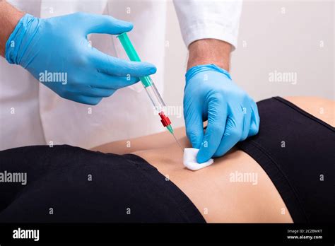 Doctor Giving Female Patient An Injection On Her Back In The Clinic