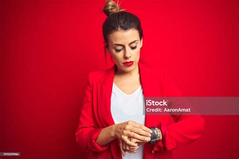빨간 고립 된 배경 위에 서있는 젊은 아름다운 비즈니스 여성 손목 시계에 시간을 확인 편안하고 자신감 가리키기에 대한 스톡 사진 및 기타 이미지 Istock