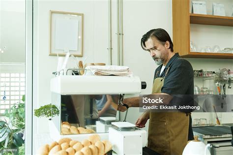 카페 내 에스프레소 머신에서 정교하게 커피를 끓이는 성인 남성 바리스타 장인의 열정과 헌신을 보여주며 가정커피사업 중소기업의